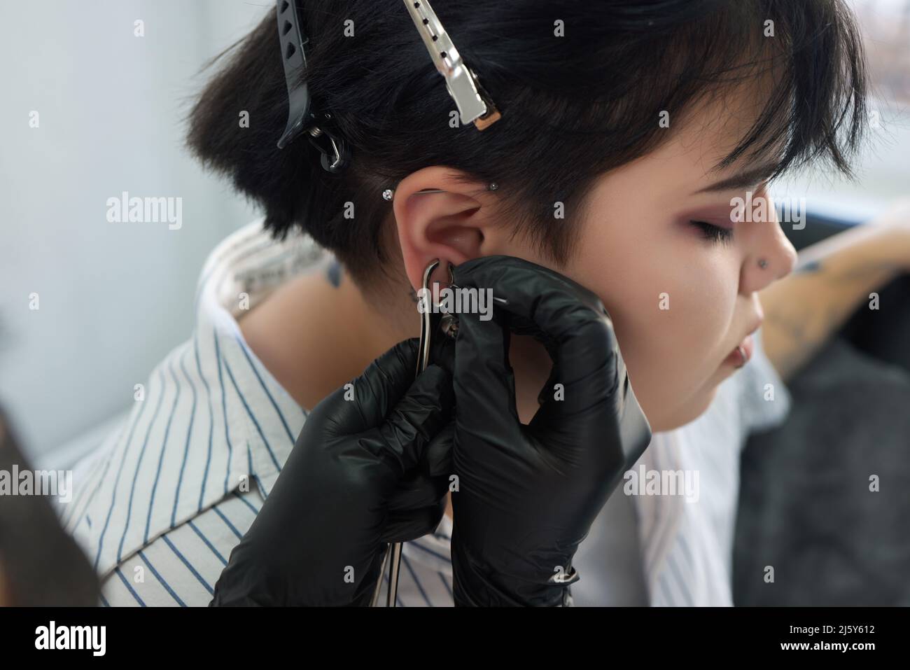 A beautician makes a puncture of the earlobe with a disposable device ...