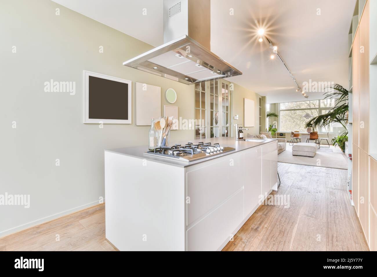 White counter with cooker and utensils placed in light spacious kitchen ...
