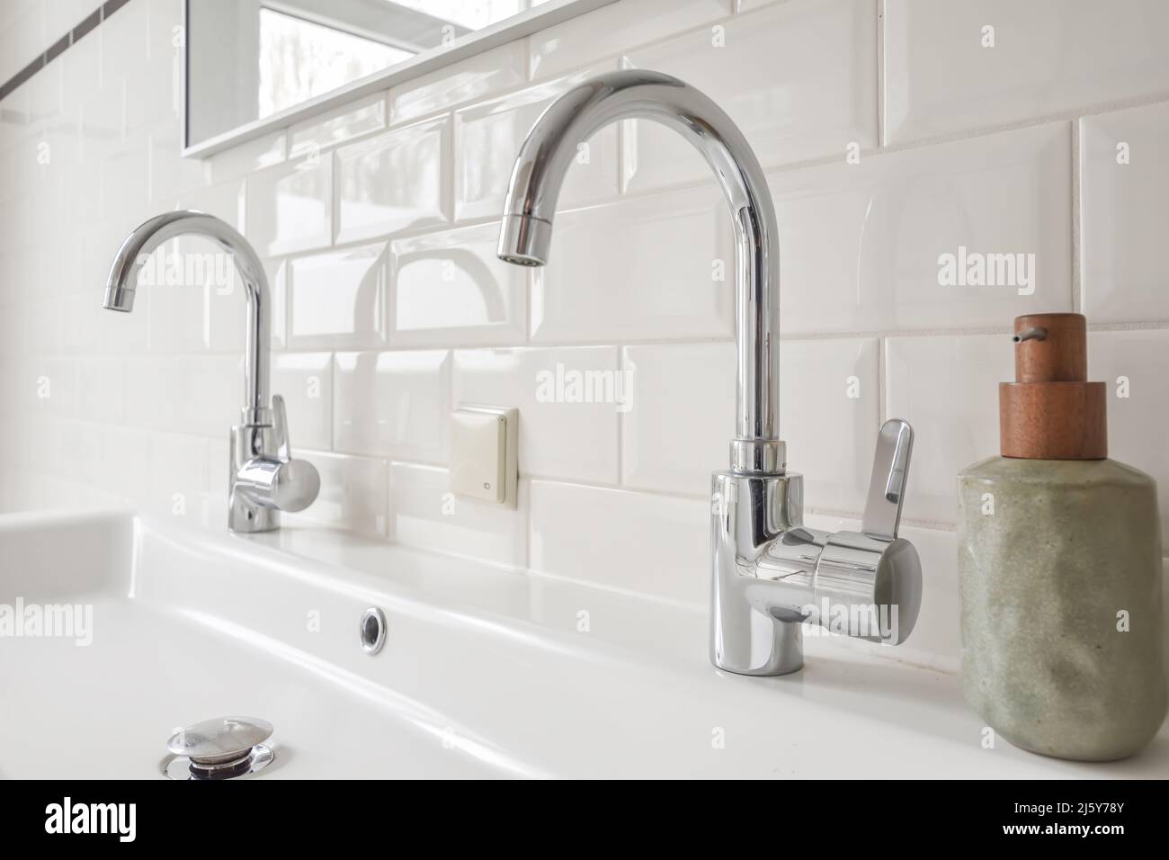 Shiny chrome faucets attached to ceramic sink in modern bathroom with ...
