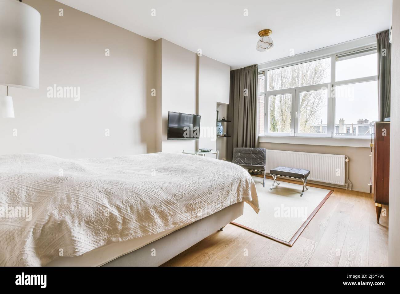 Comfortable bed with coverlet in spacious cozy bedroom with ...