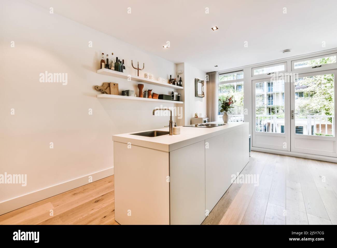 White counter with sink placed at wall with various supplies on shelves ...