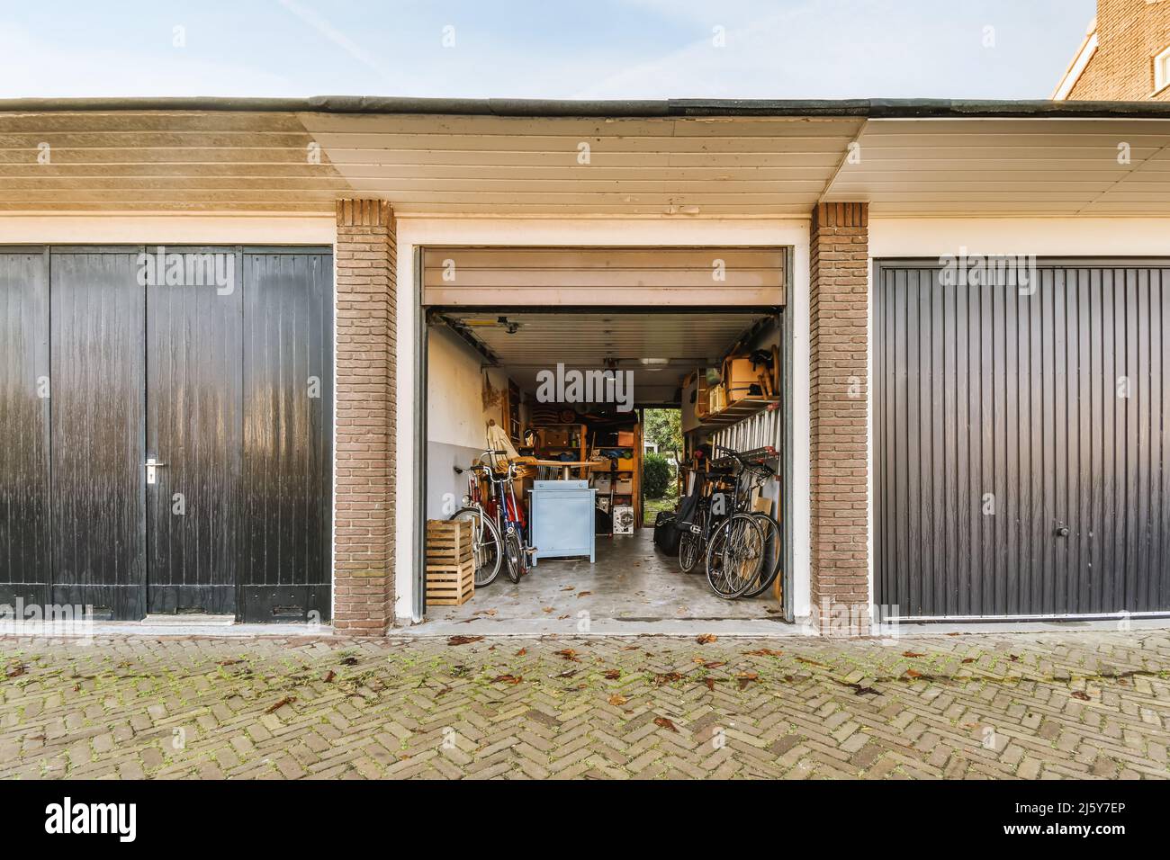 Opened metal garage with parked bicycles and wooden boxes with various ...