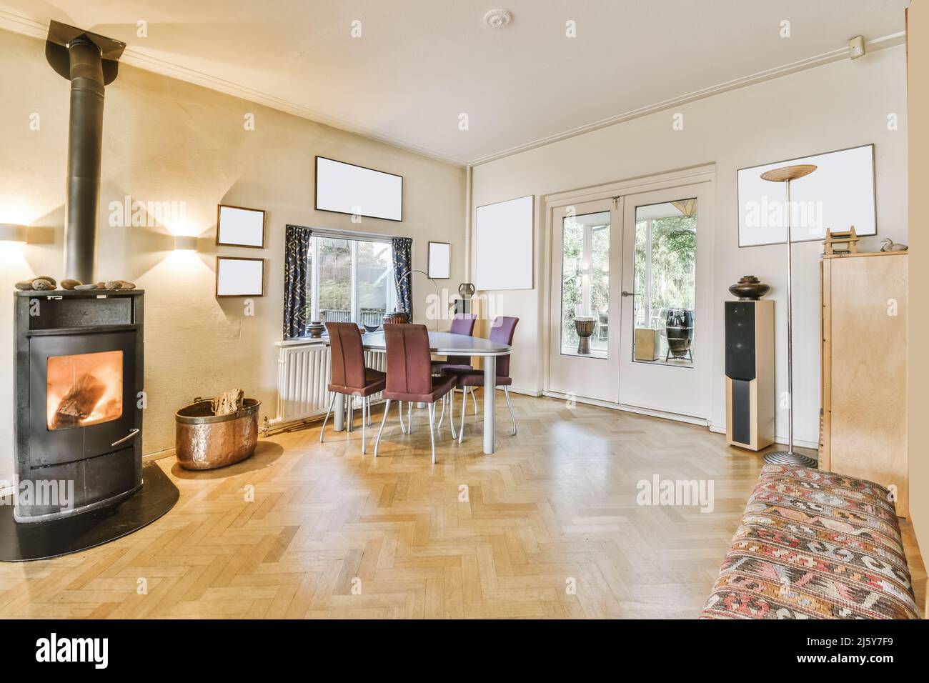 Chairs at table near black metal furnace with burning firewood in light ...