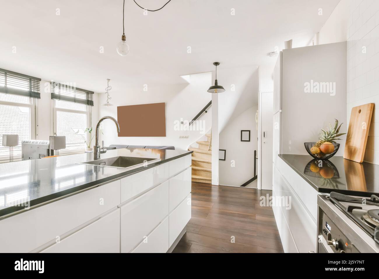 Large kitchen with two black countertops and at the back a living room ...