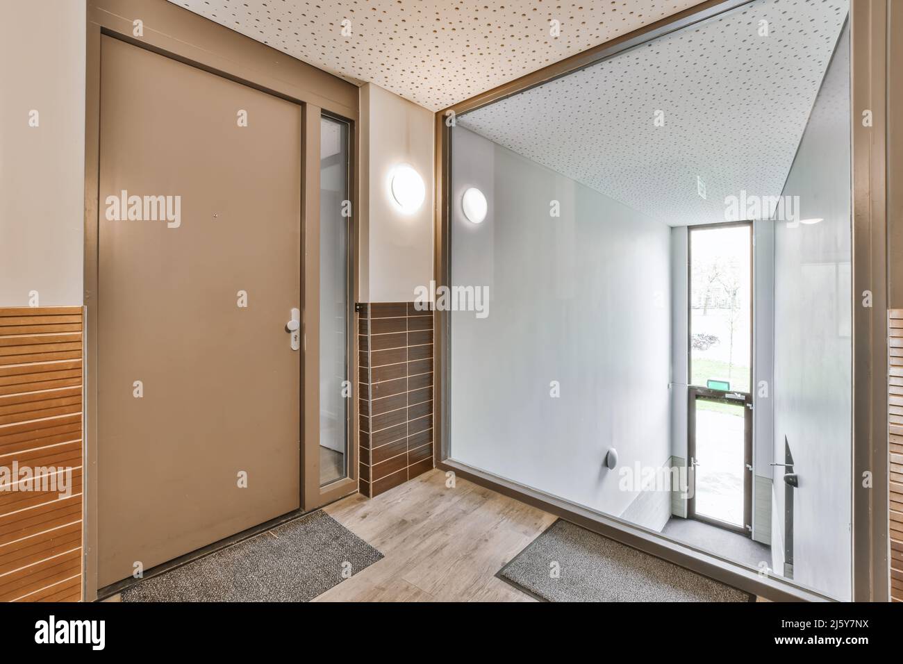 Spacious corridor with closed entrance door near glowing lamp and big ...
