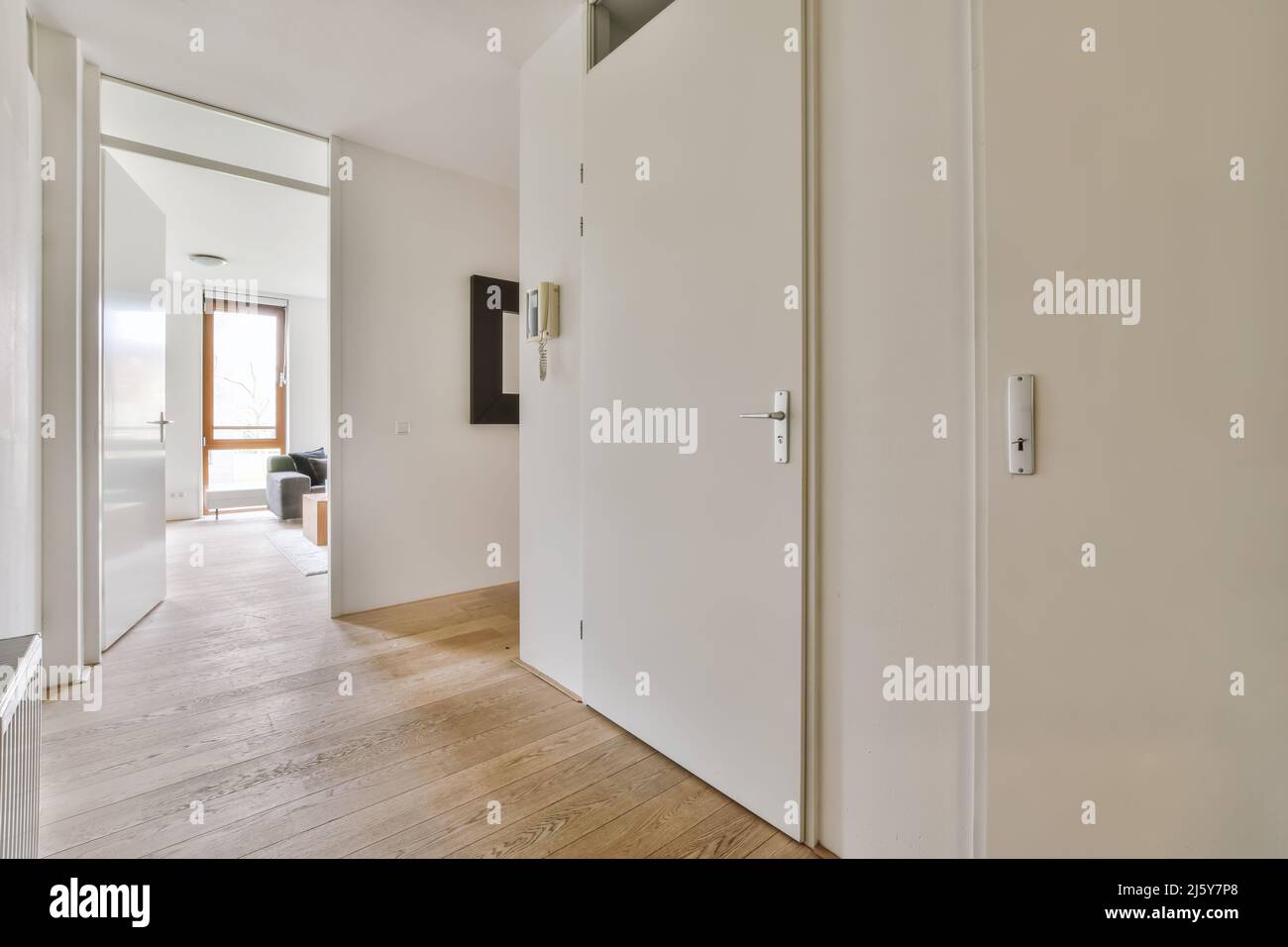 Stylish corridor with white walls leading to opened door of room with ...