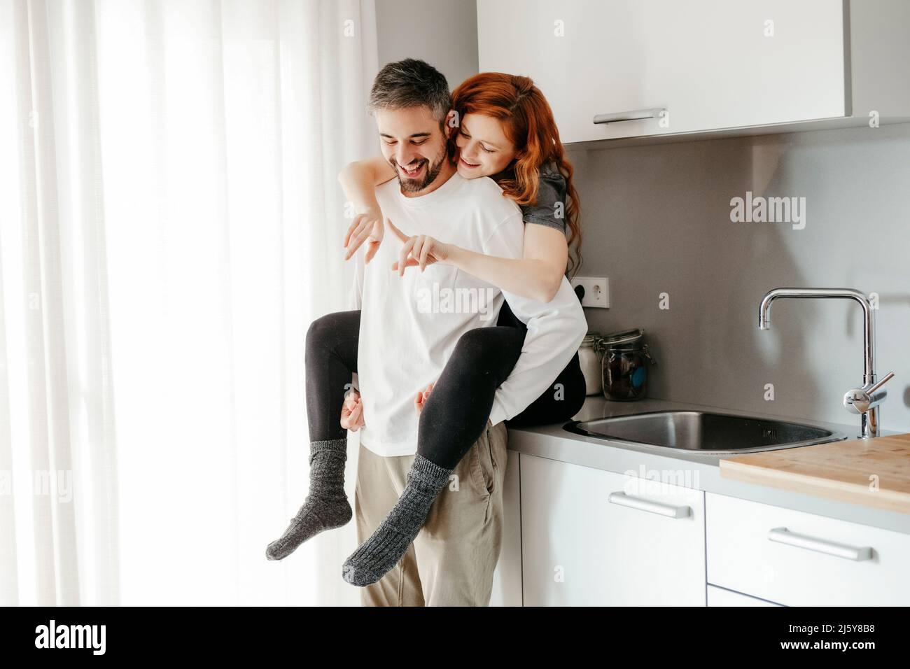 Romantic couple in casual wear embracing in piggyback position while ...