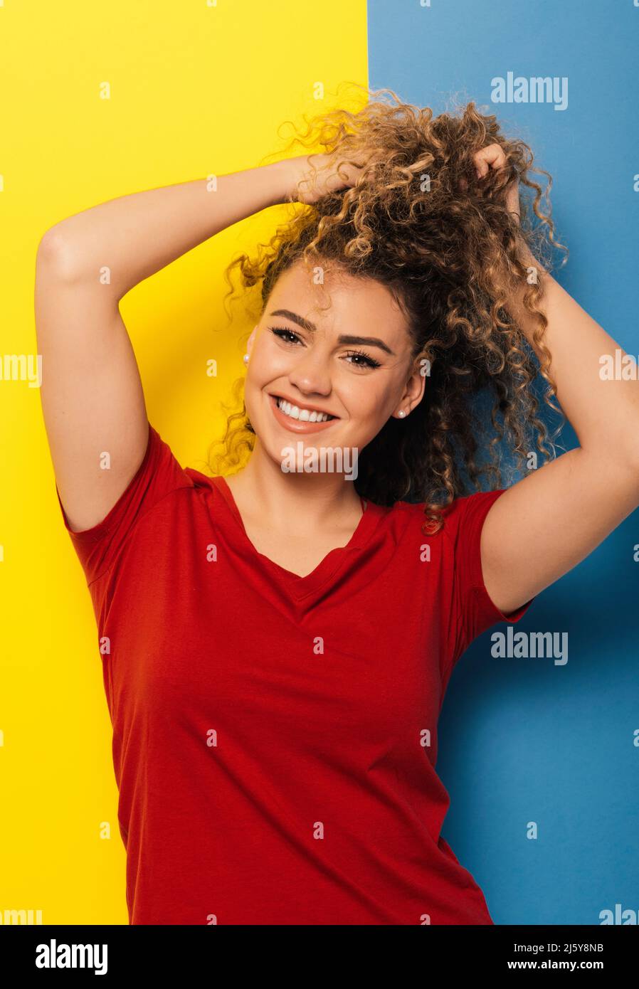 Happy young Woman in bright yellow sweater and jeans. She is ruffling ...