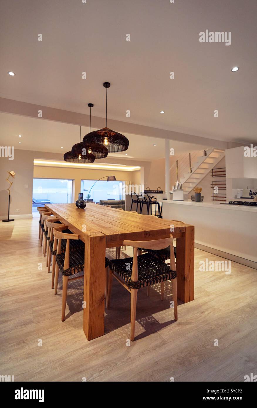 Black pendant lights over long wooden dining table in modern home Stock ...