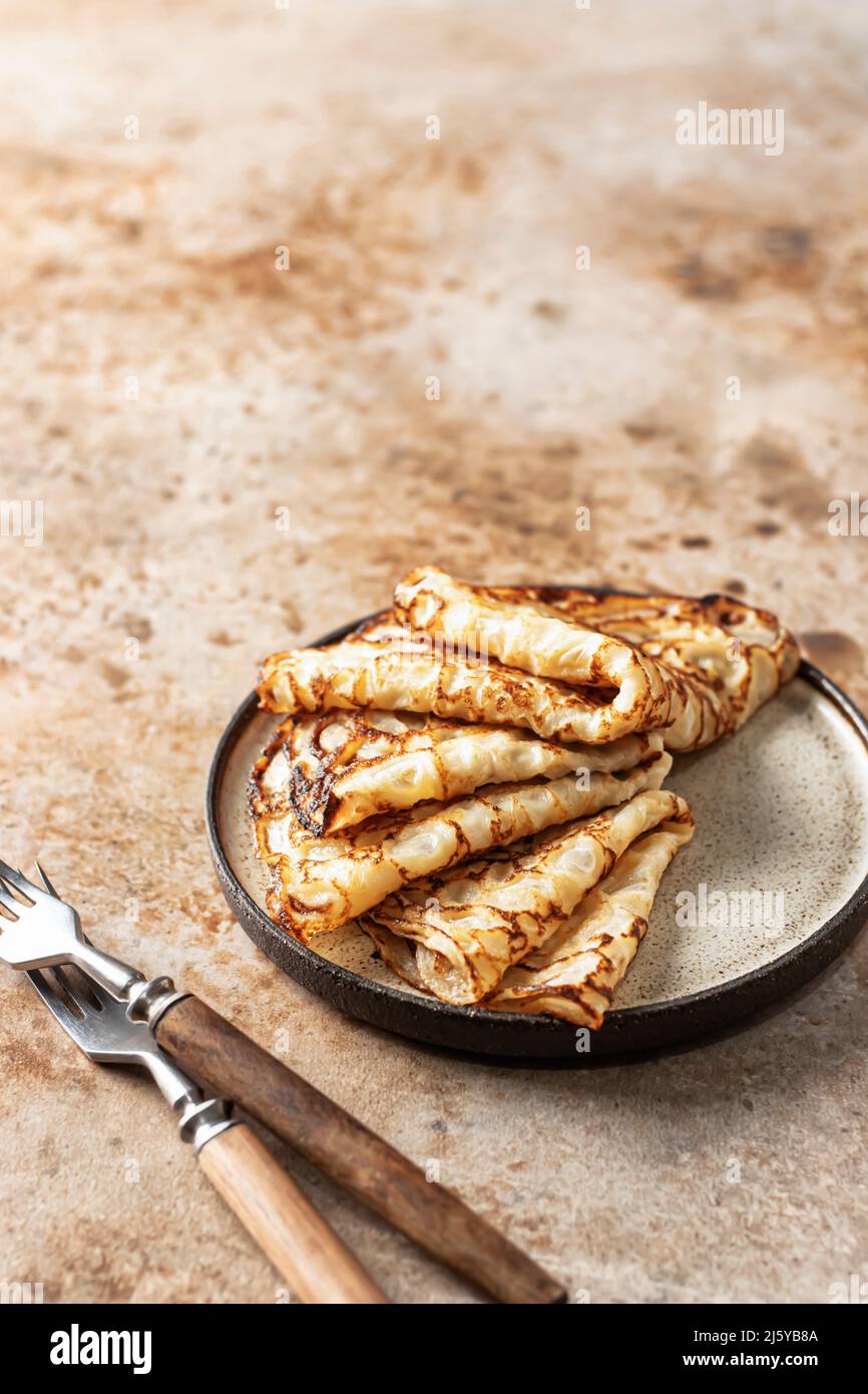 Crepes in brown plate with two rustic forks. Vertical orientation. Copy ...
