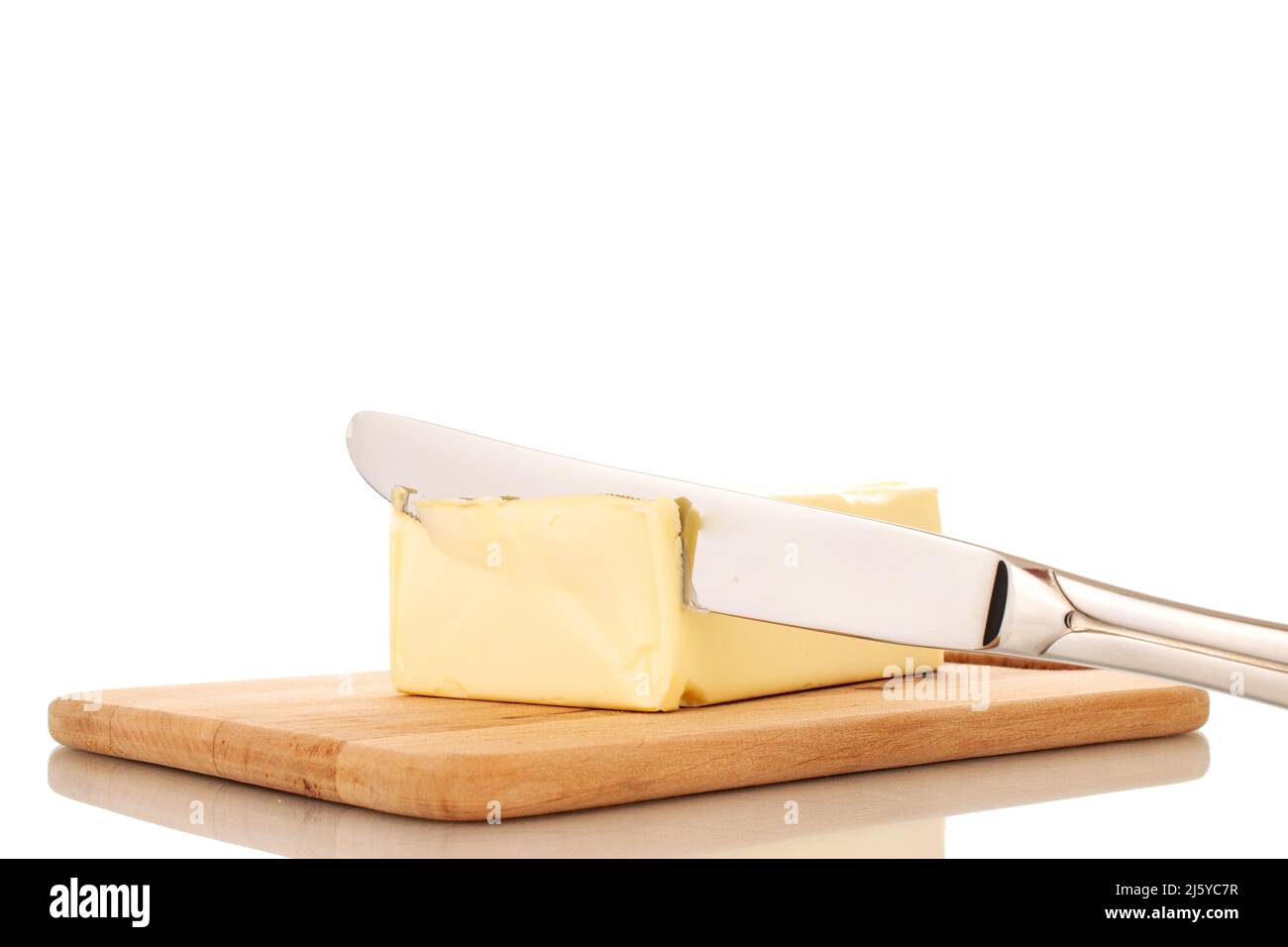 One piece of delicious butter with a metal knife on a wooden cutting ...