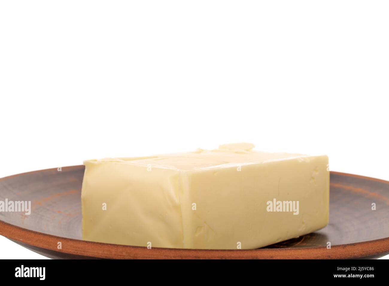 One piece of delicious butter on a ceramic plate, close-up, isolated on ...