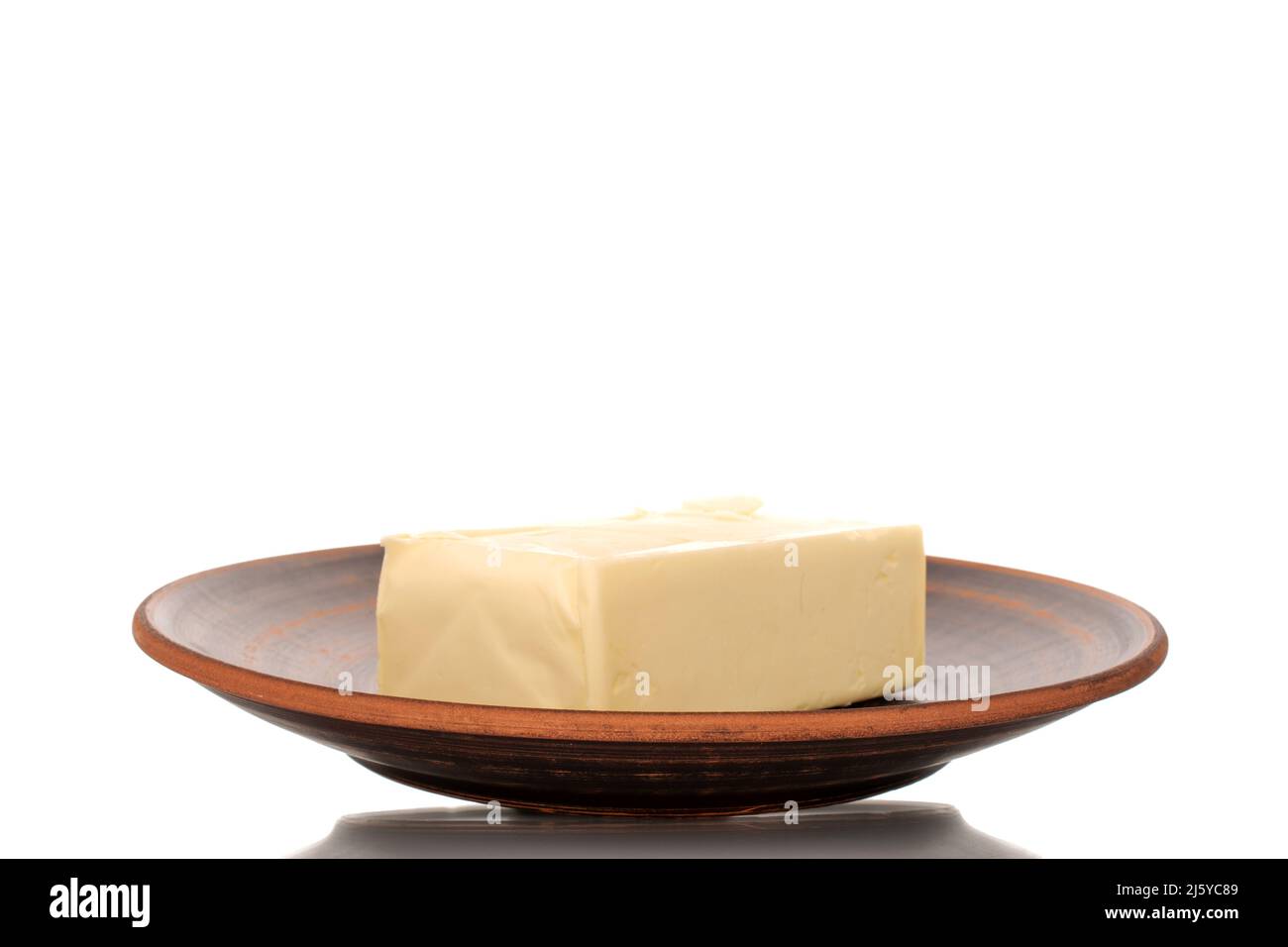 One piece of delicious butter on a ceramic plate, close-up, isolated on ...