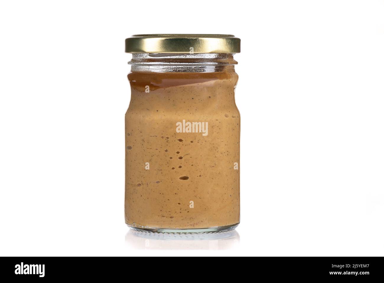 Close-up of mustard in a transparent glass jar with a closed gilded ...