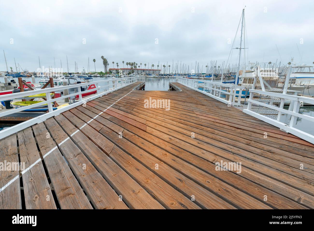 Wood planks flooring on a harbor dock with white fence barrier at ...