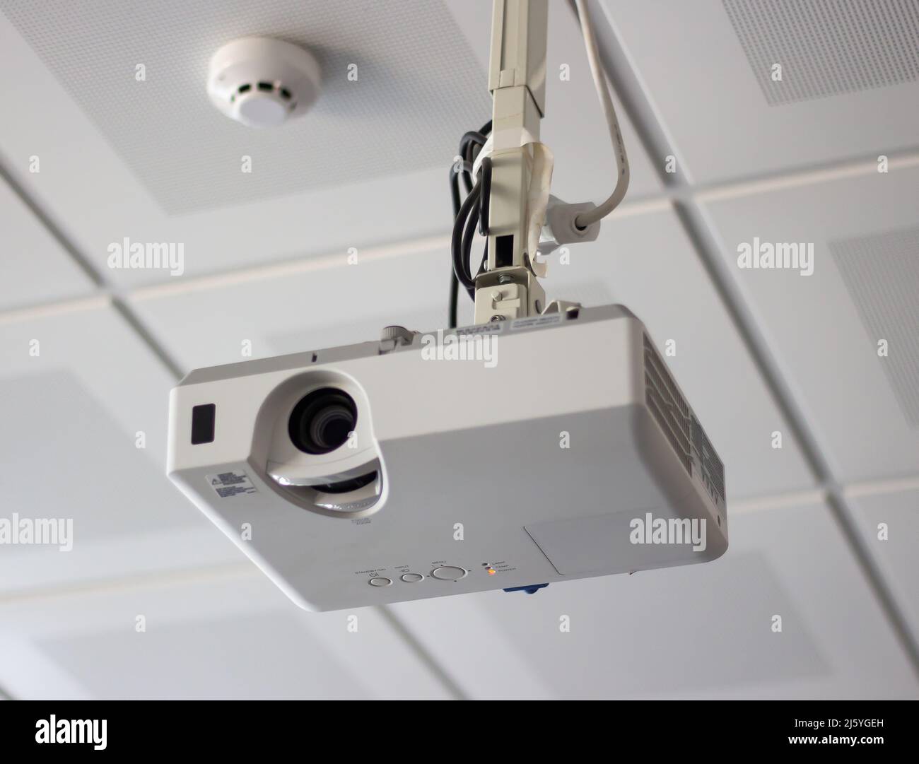 White overhead multimedia projector hanging on the ceiling in ...