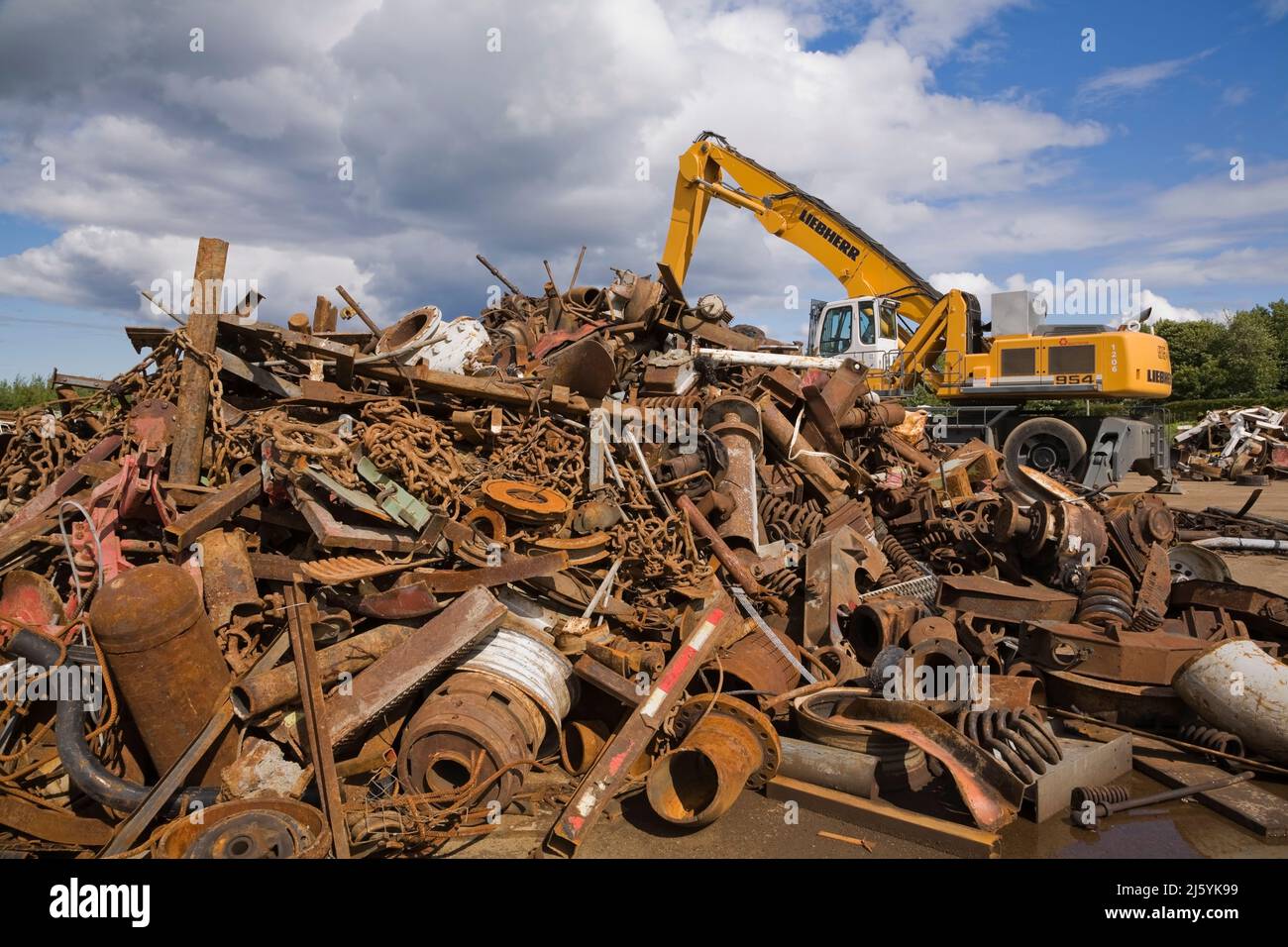Crane loader with grappling arm and assorted discarded rusted ferous ...