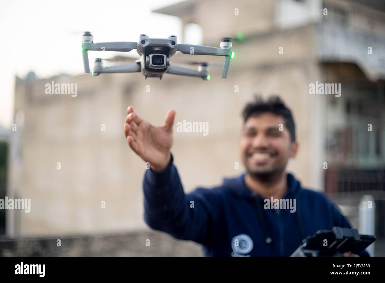 young indian male catching launching folding drone with camera from ...