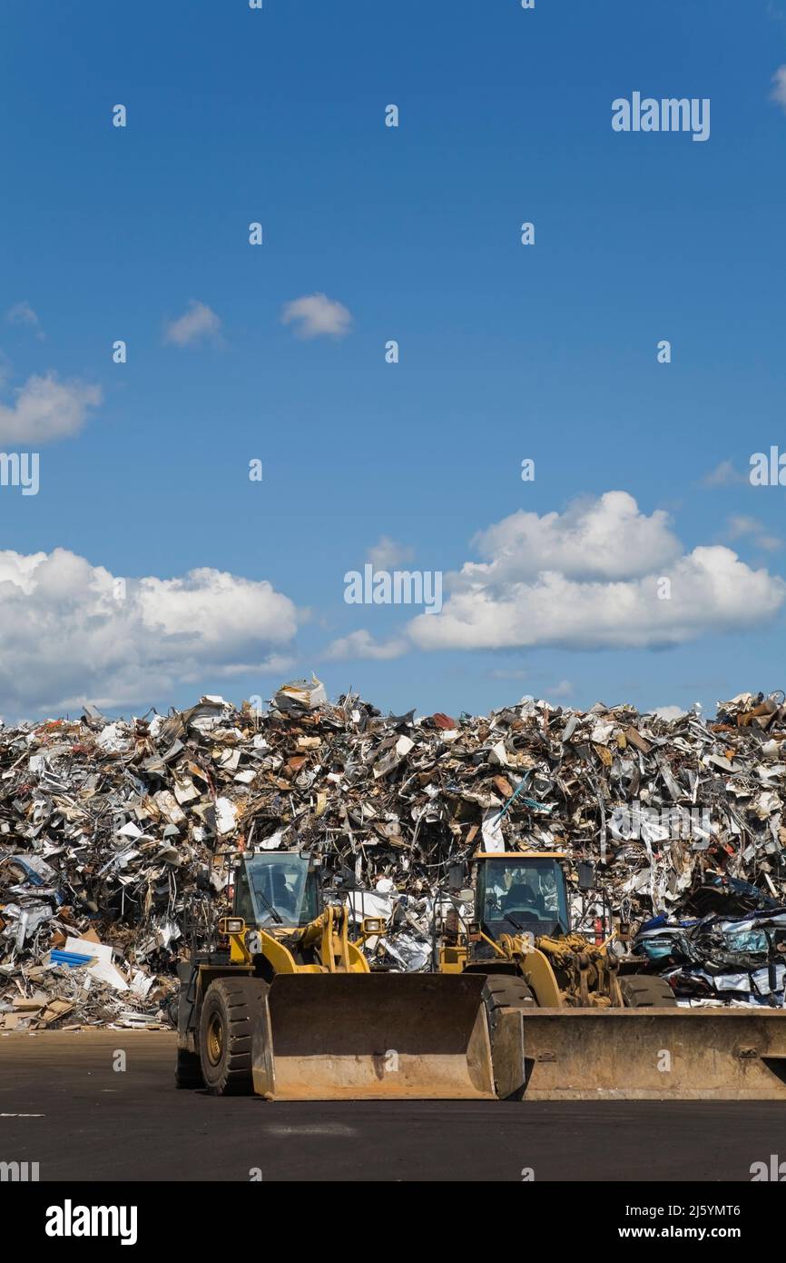 Front-end loaders in front of a pile of discarded metal household and ...