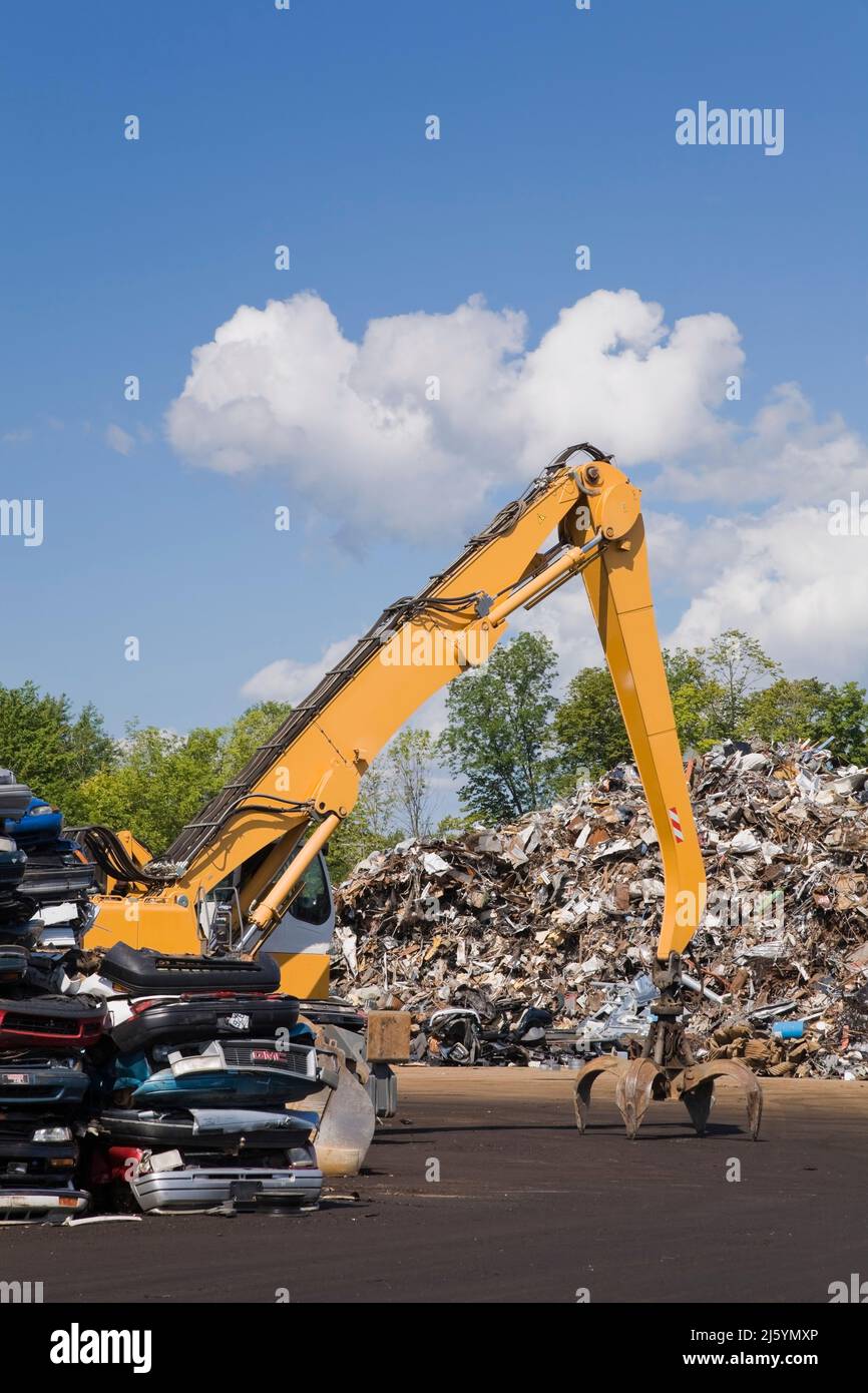 Crane loader with grappling arm fitted with claw clamp in front of pile ...