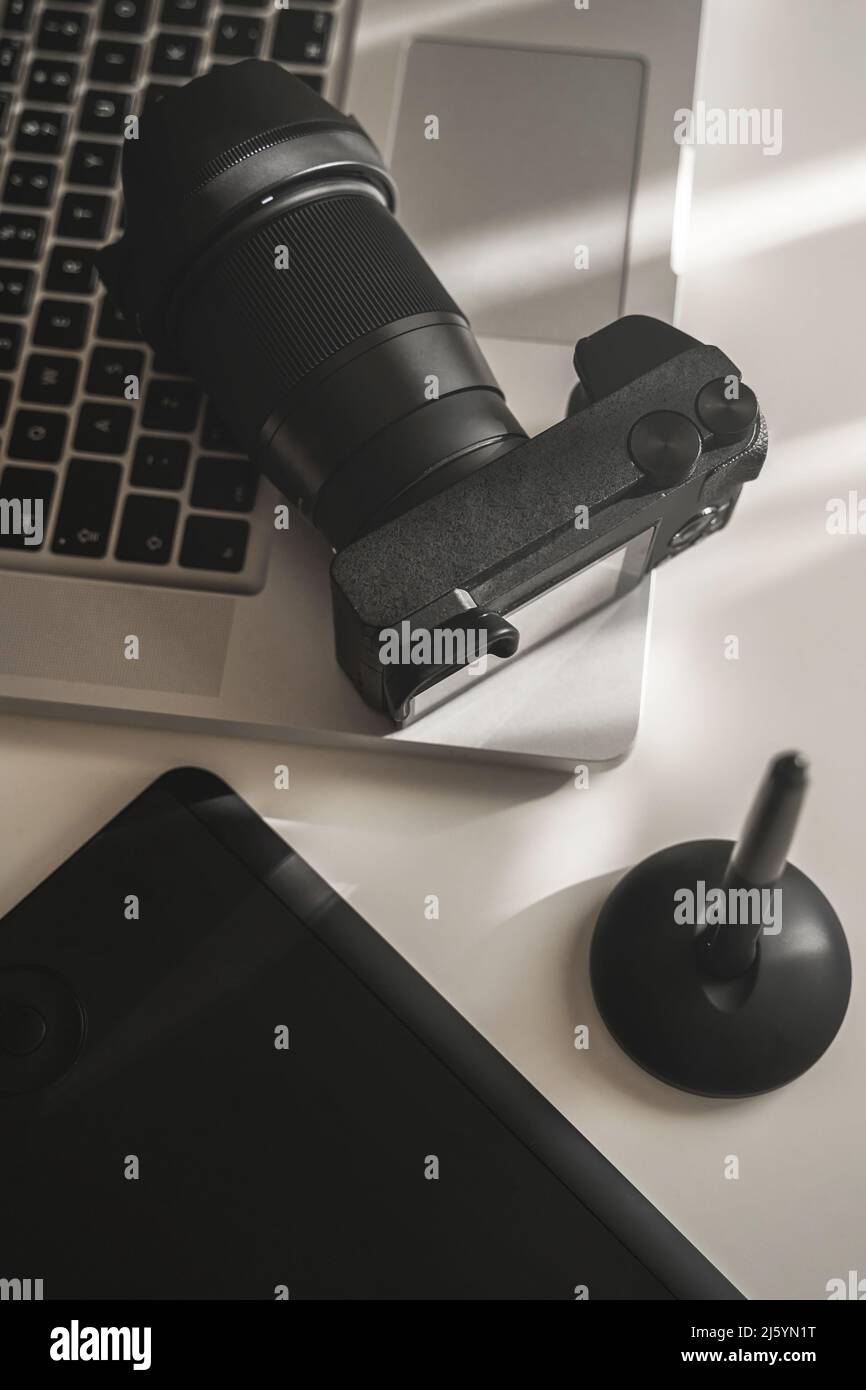 Photographer's workplace with a mirrorless camera, laptop and graphics ...
