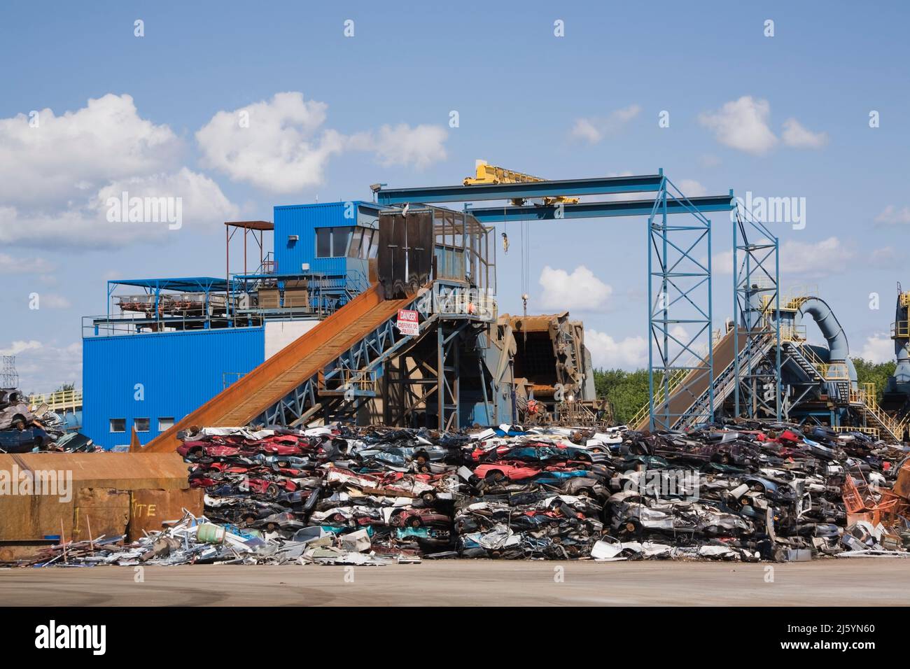 Stacked and crushed automobiles and industrial metal shredder at a ...