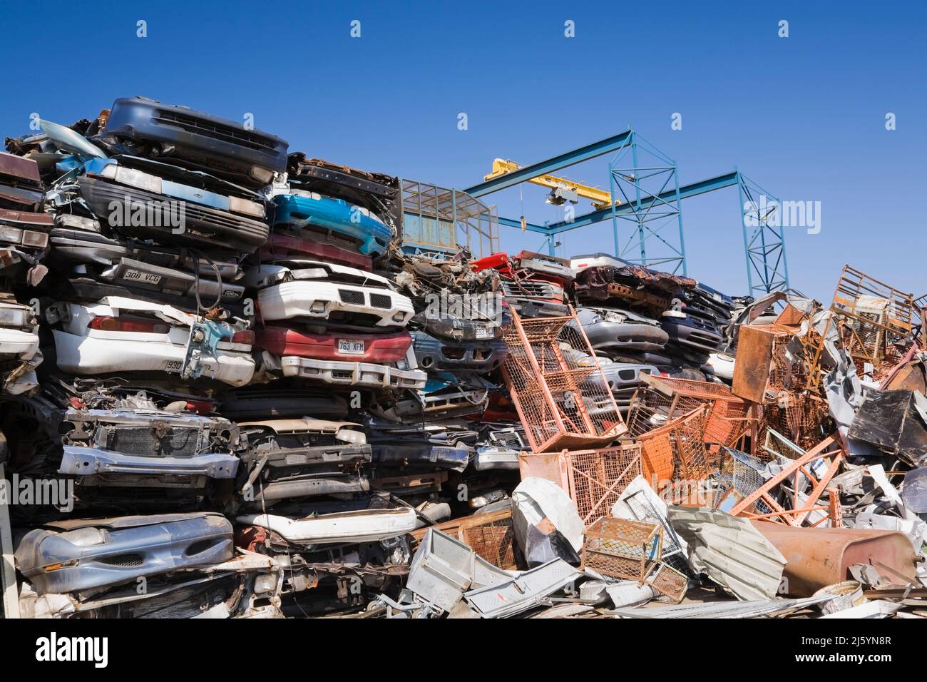 Stacked and crushed automobiles and pile of metal racks at a scrap ...