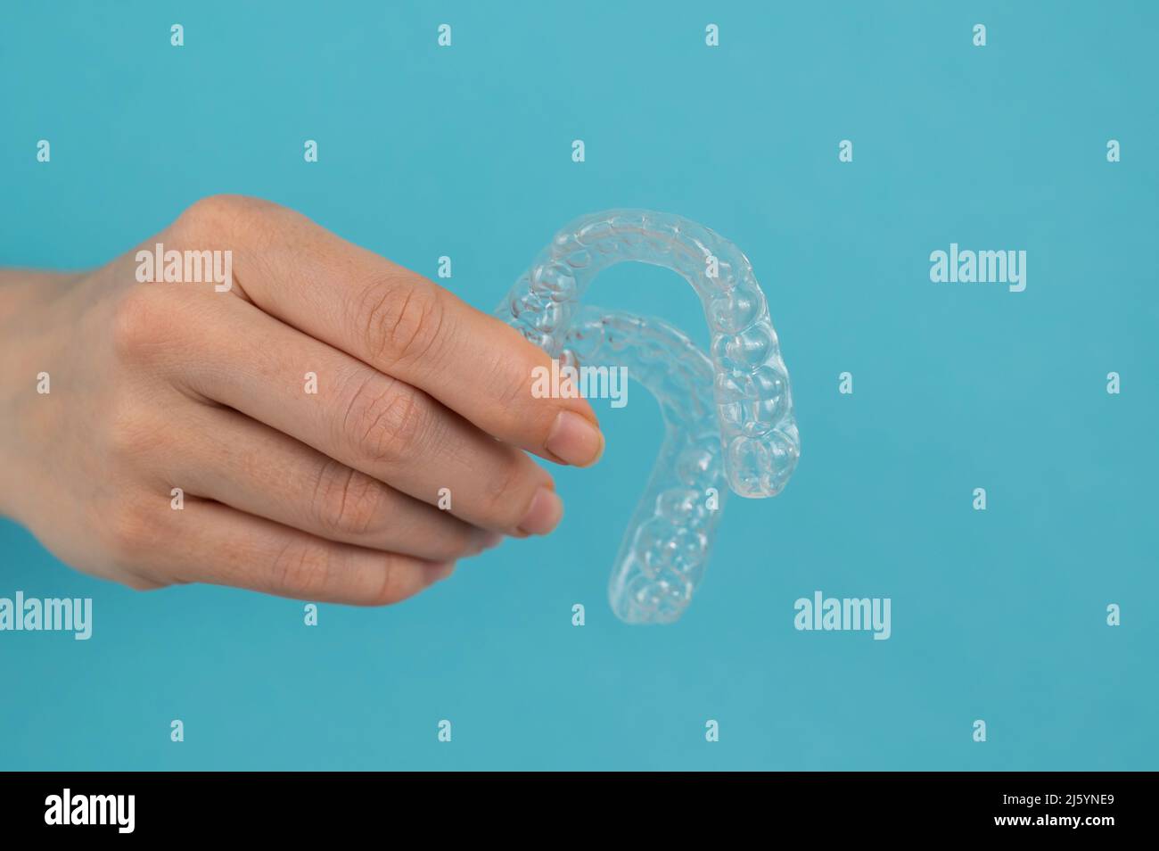 A female hand sticking out of a hole from a blue background holds ...
