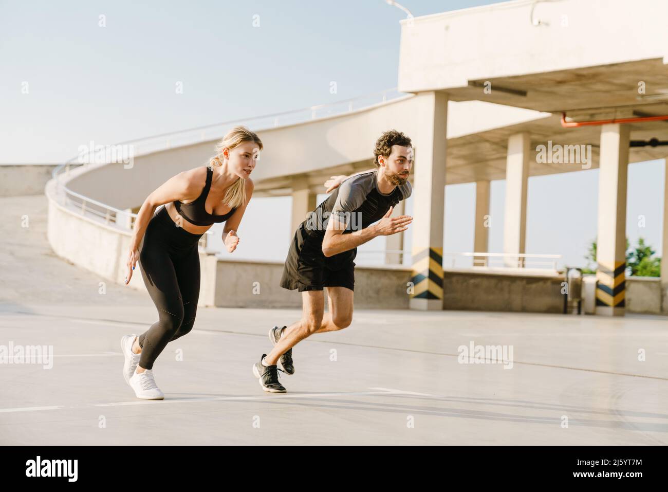 Young runners doing exercise while working out together on parking ...