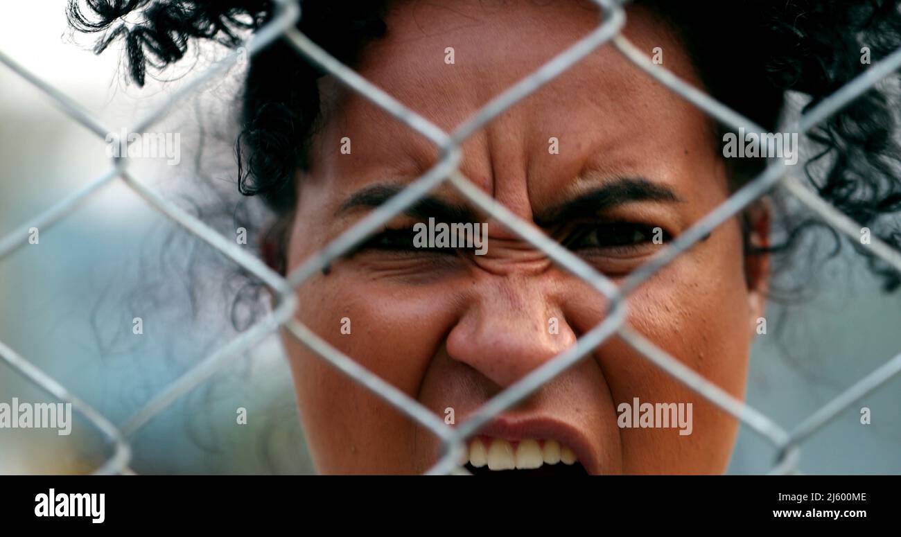 Angry upset african woman yelling seen through metal fence barrier ...