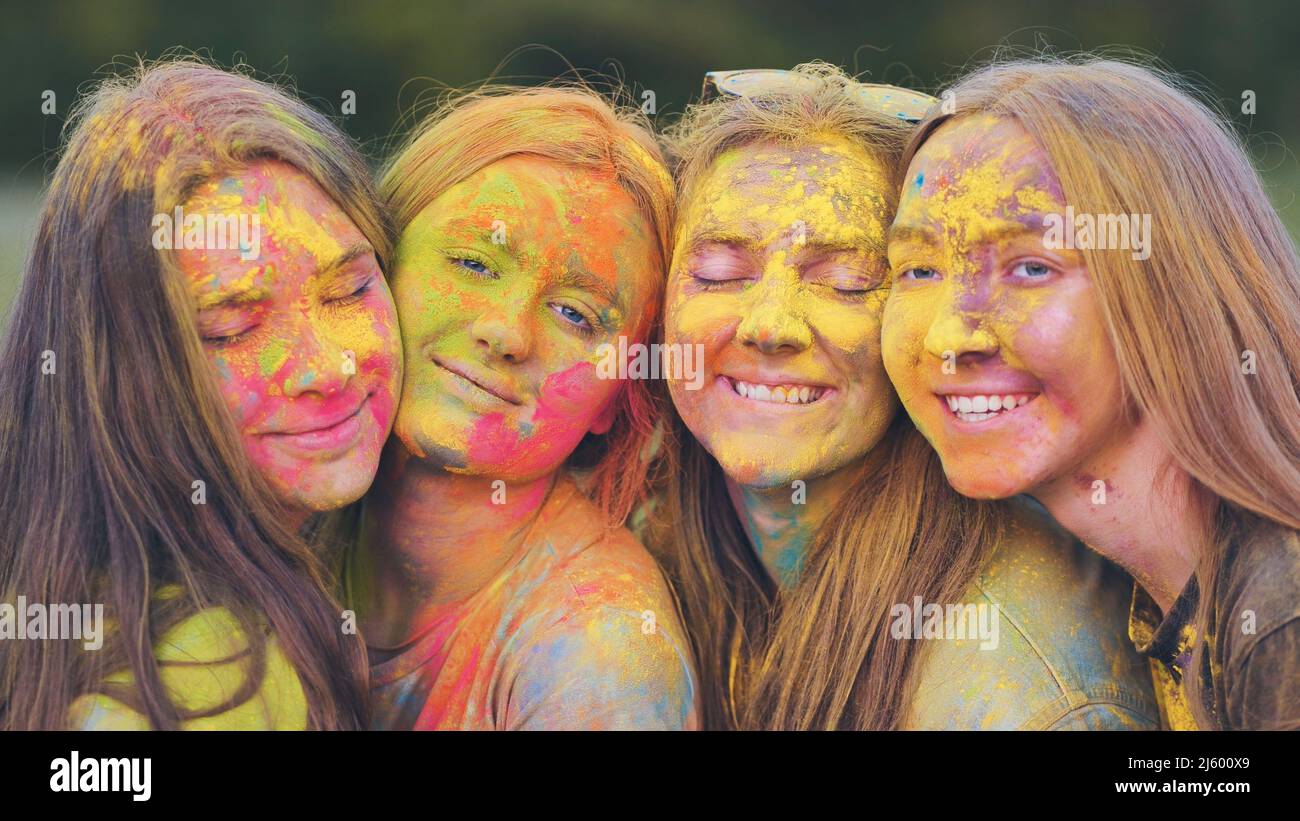 Cheerful girls posing smeared in multi-colored powder. Close-up faces ...