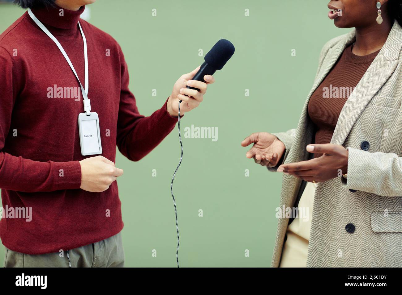 Medium section of young gallerist holding microphone taking interview ...