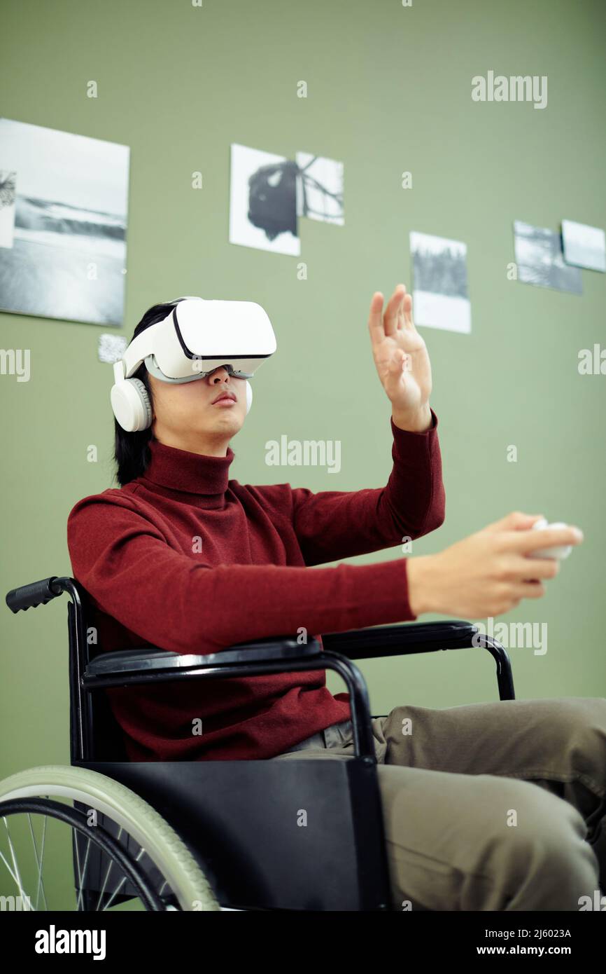 Young Asian man with disability wearing VR headset visiting ...