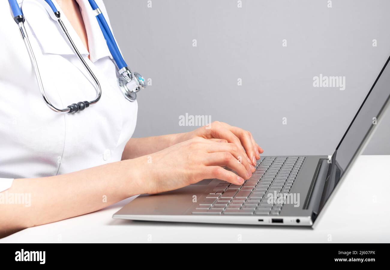 Doctor hands closeup typing on laptop keyboard. Woman in lab coat ...