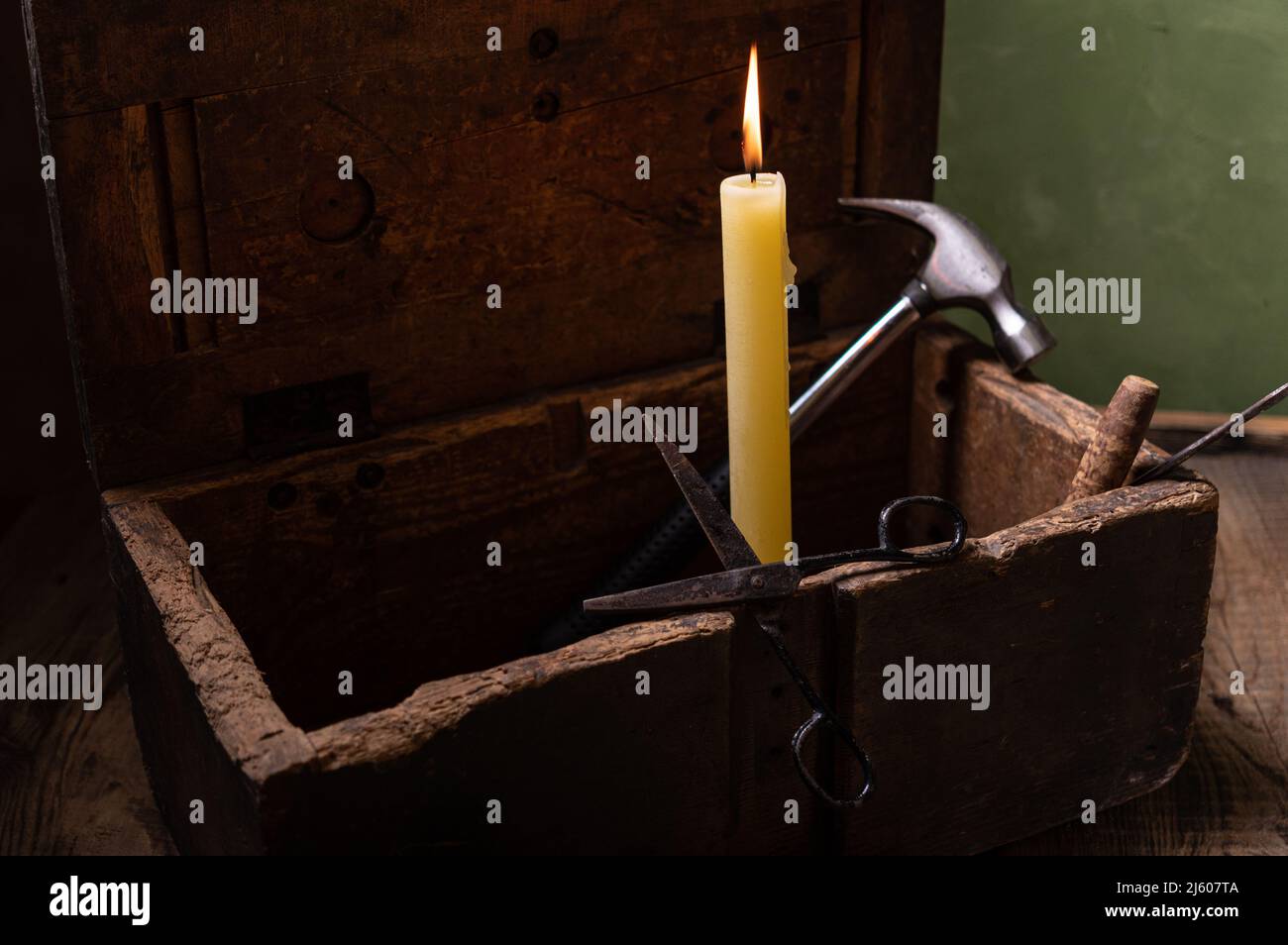 Burning candle in a dark room. The candle is in an old wooden box ...