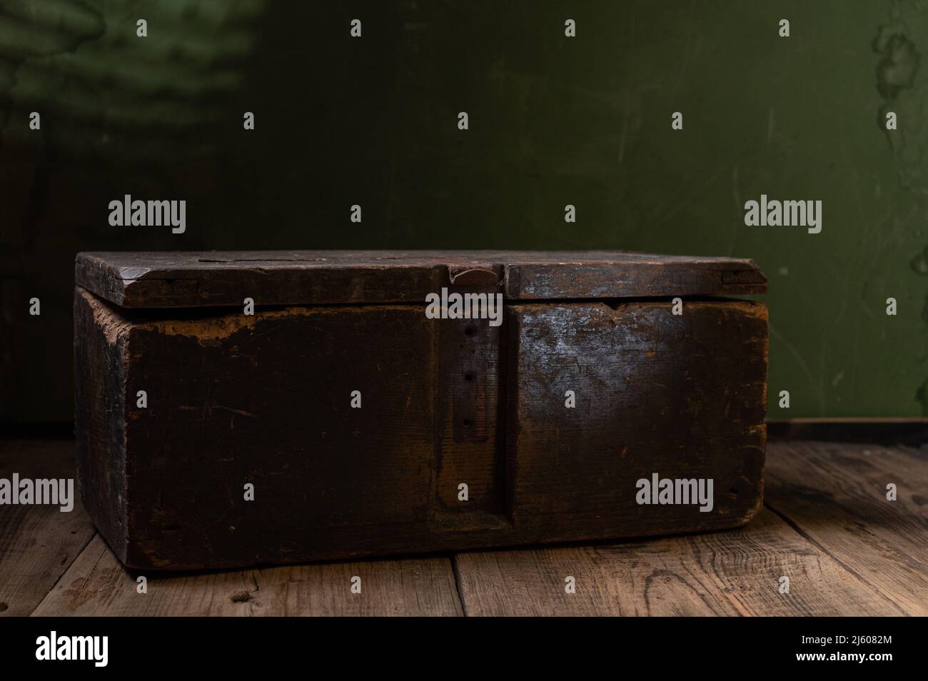 An old box in a dark room. Old closed wooden box. Cache in a wooden box ...