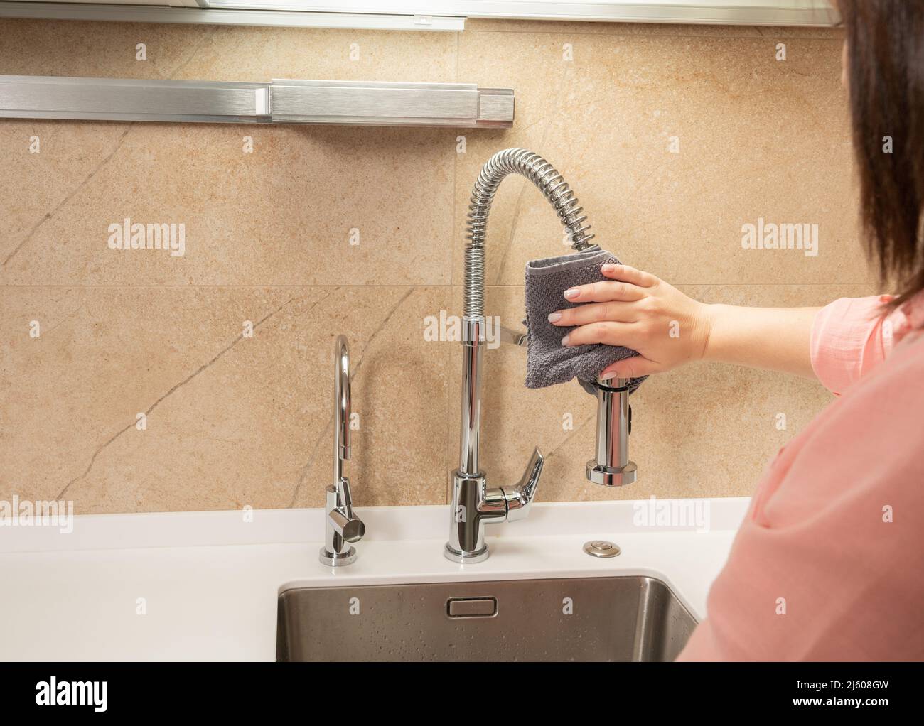 polishing metal surfaces with a rag in the kitchen Stock Photo - Alamy
