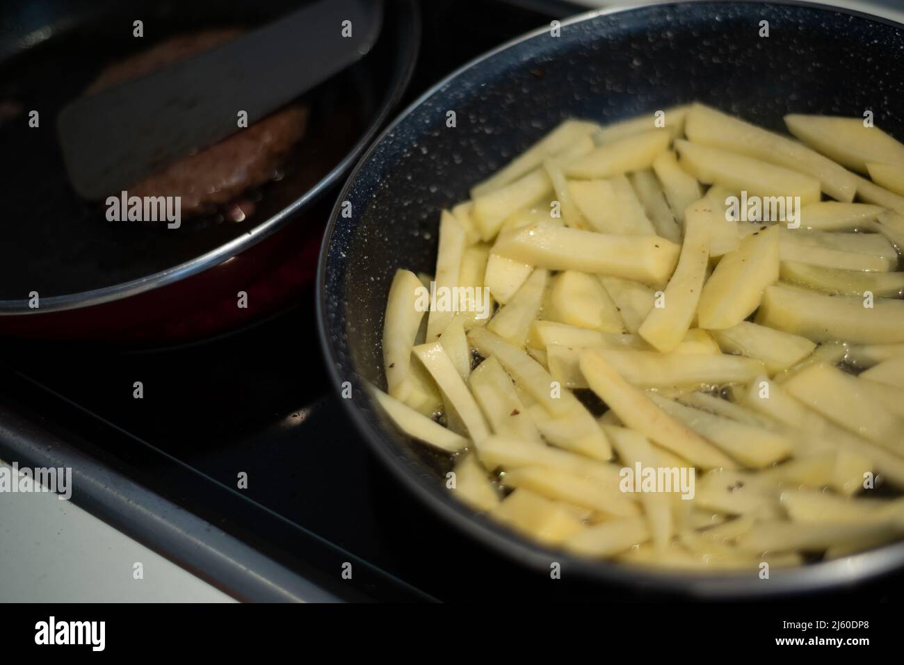 Cooking fresh meat and fries in oily saucepan Stock Photo - Alamy