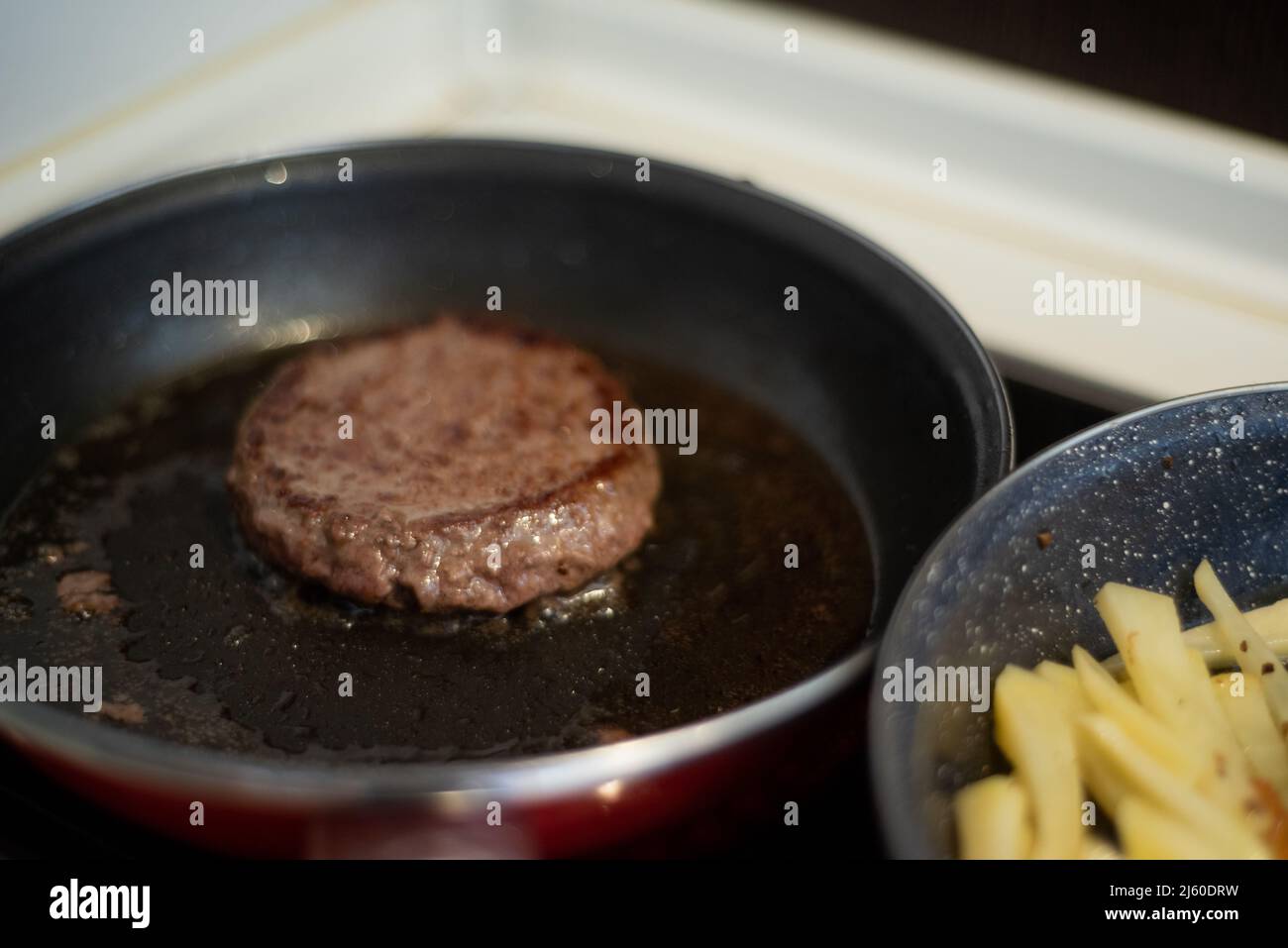 Cooking fresh meat and fries in oily saucepan Stock Photo - Alamy