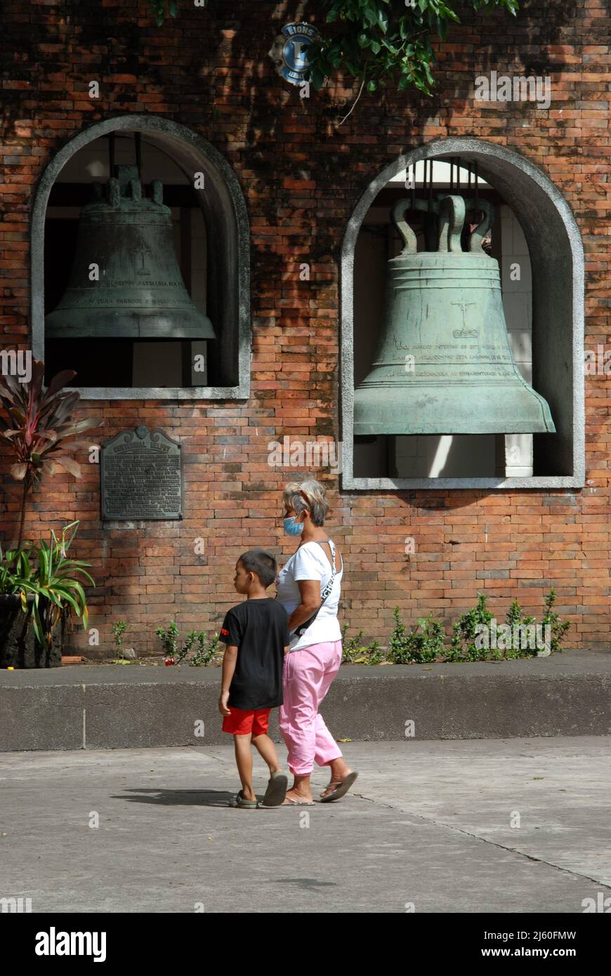 Grandmother and boy walking past large bells, San Sebastian Cathedral ...