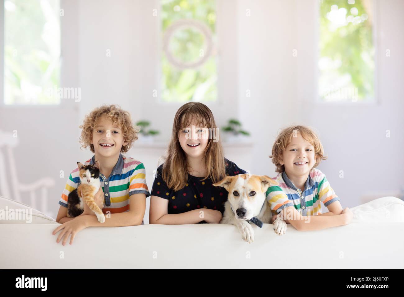 Kids play and watch tv on white couch. Children at home. Sunny family ...