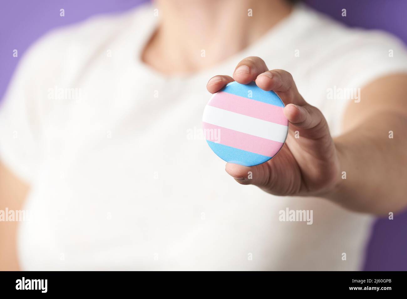 Unrecognizable person showing to the camera a trans flag badge or pin ...