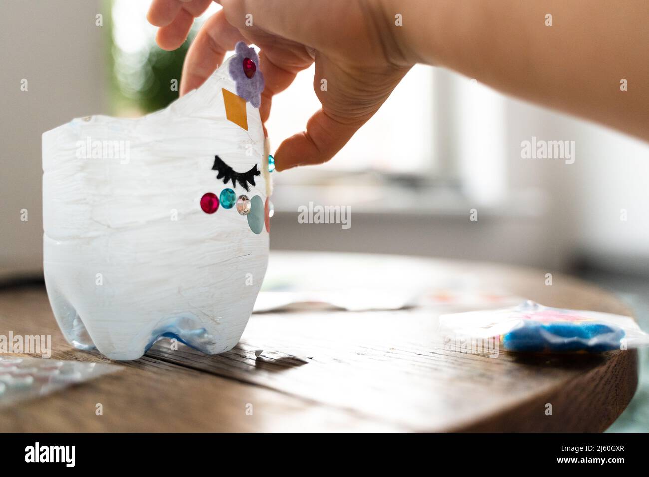 Caucasian preschool girl doing crafts with plastic bottle and paints ...