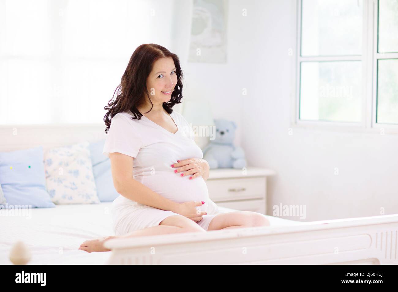 Pregnant woman at home. Young expecting mother in white bedroom ...