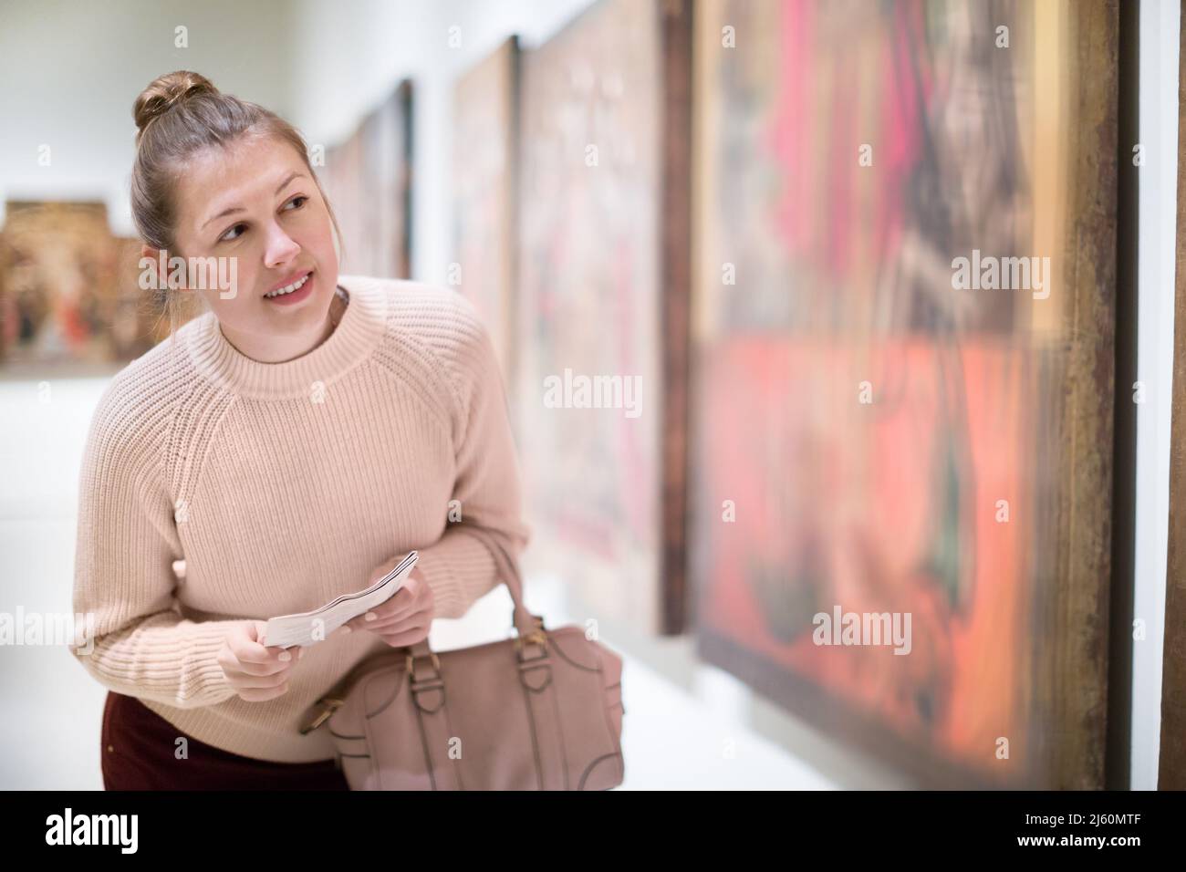 Woman with guide looking at pictures in museum Stock Photo - Alamy