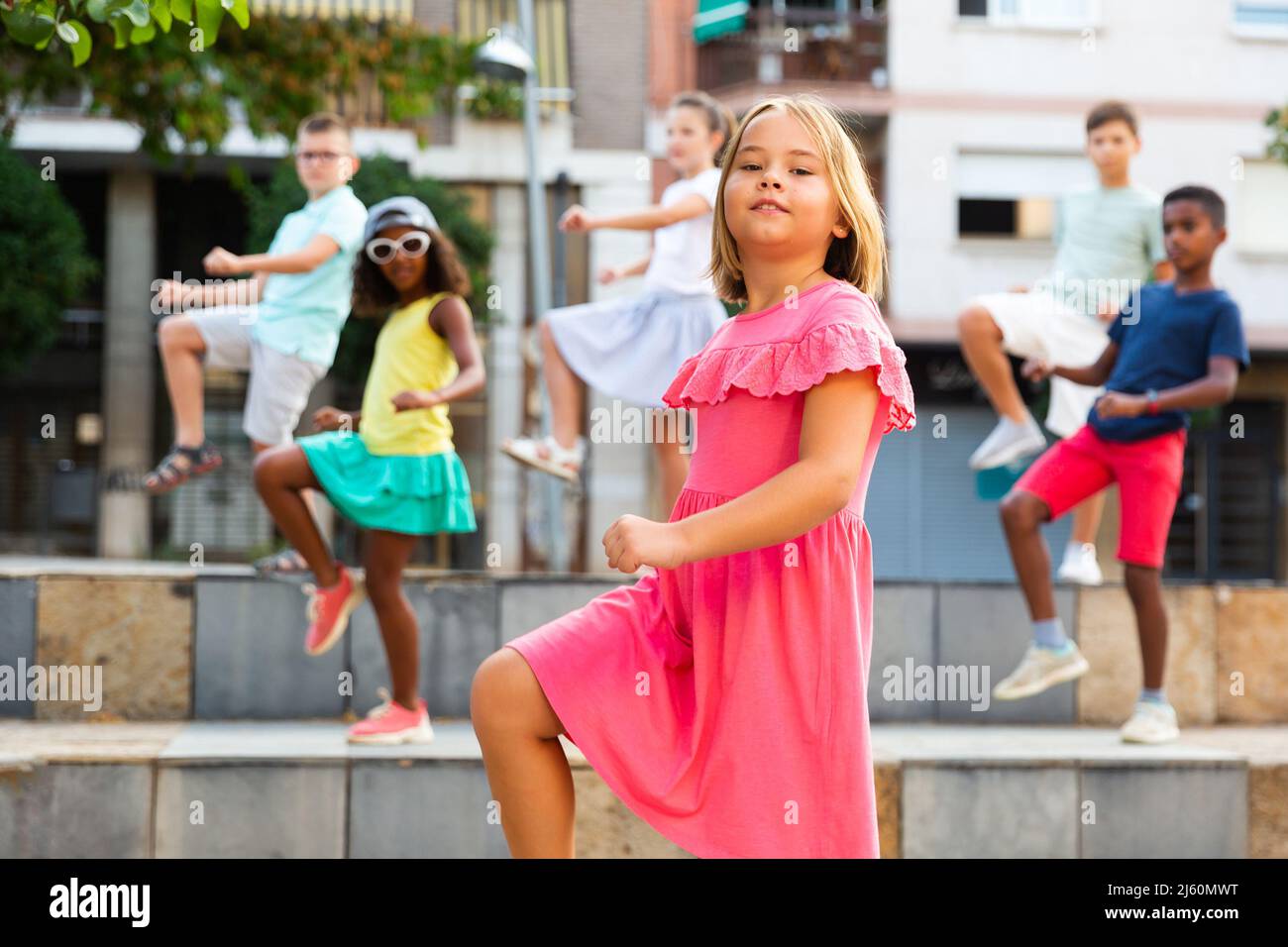 Preteen girl dancing with group of friends on city street Stock Photo ...