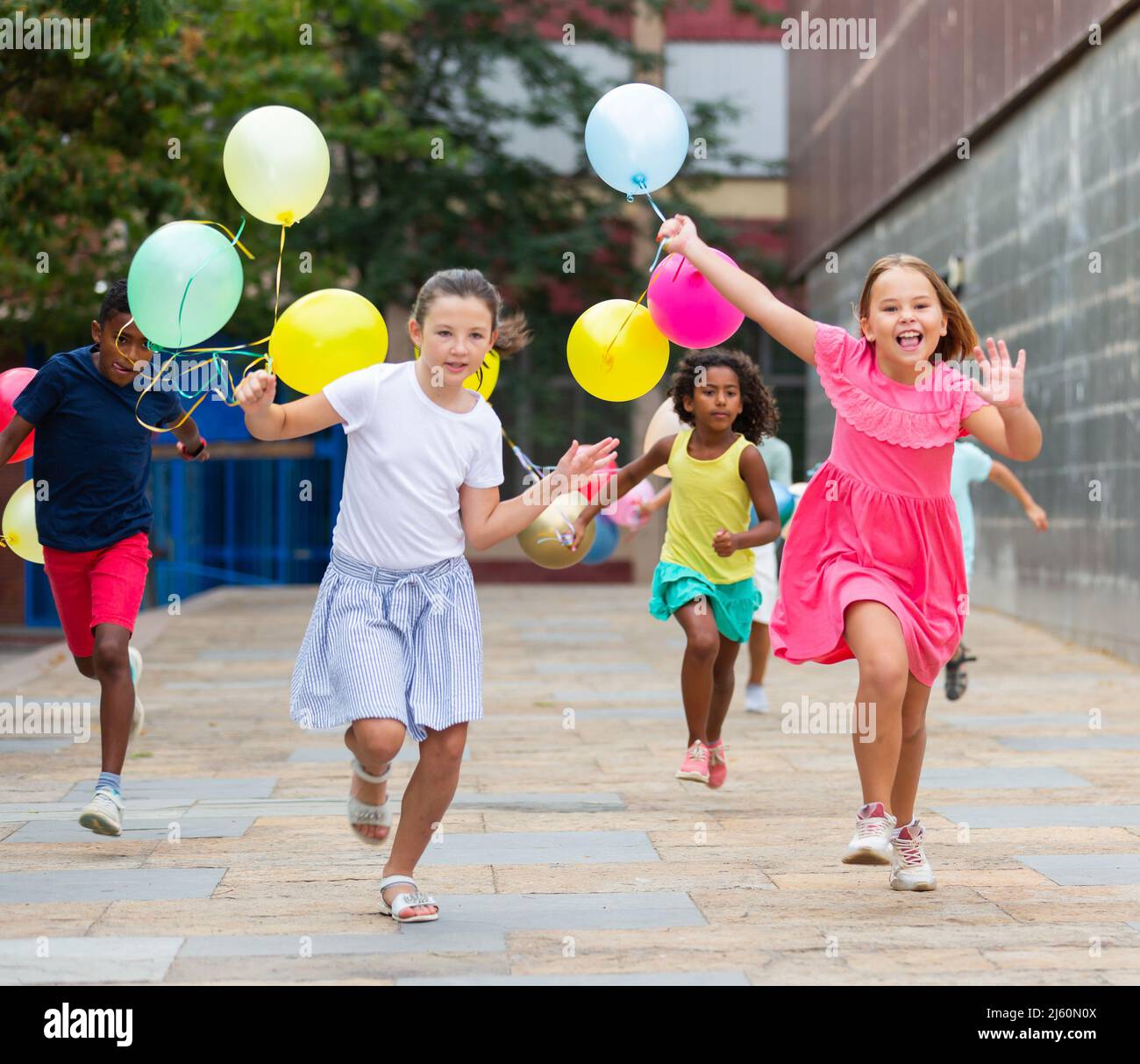 Kids with balloons running through streets Stock Photo - Alamy