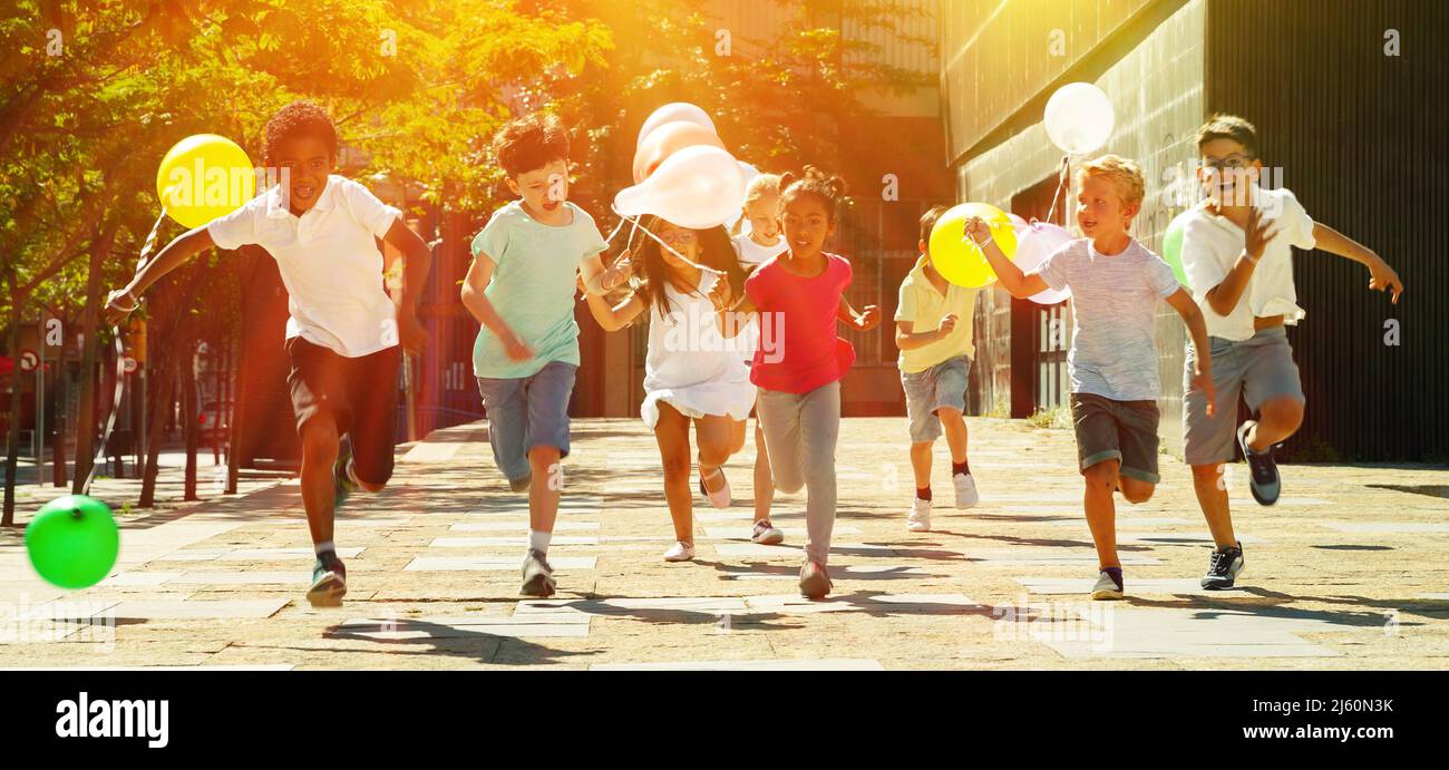 Happy children with balloons run on the summer city street Stock Photo ...