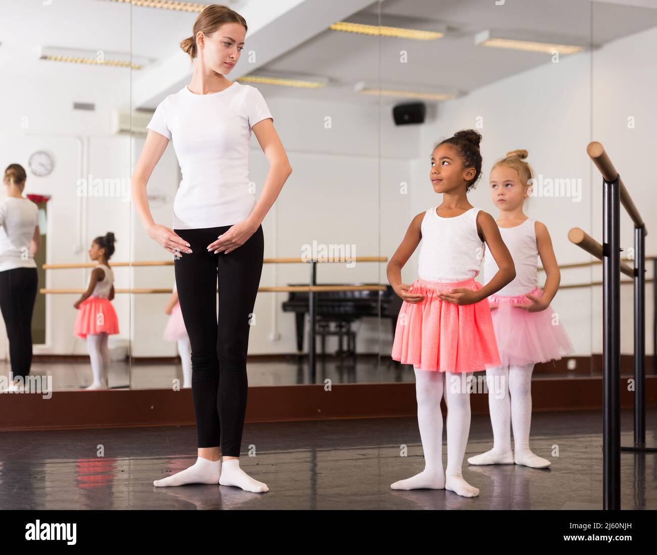 Dance teacher helping her little girls students Stock Photo - Alamy