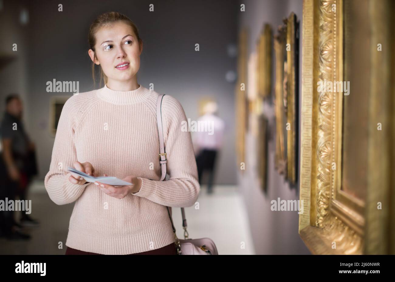 Woman with guide looking at pictures in museum Stock Photo - Alamy